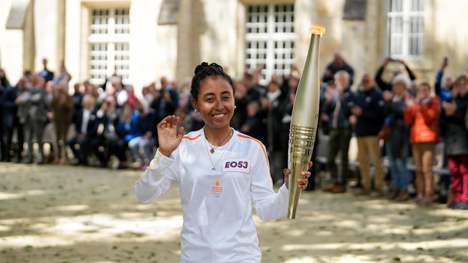 Refugee Olympic Team cyclist carries the Olympic flame